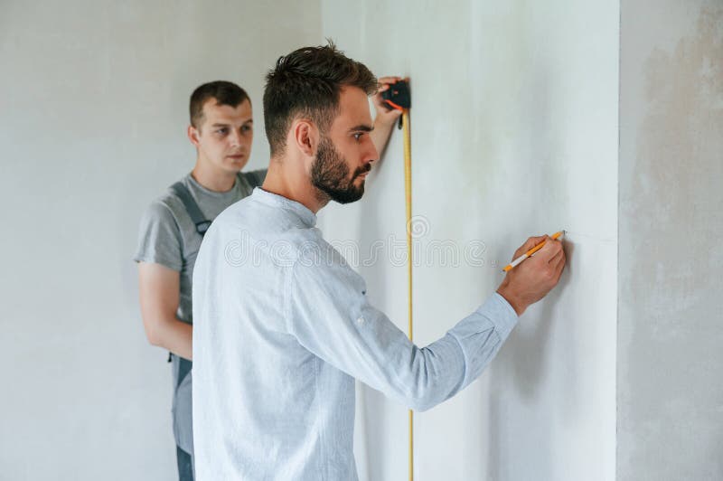 Measuring the Wall by Roller. Two Men is Making Repairs in the ...