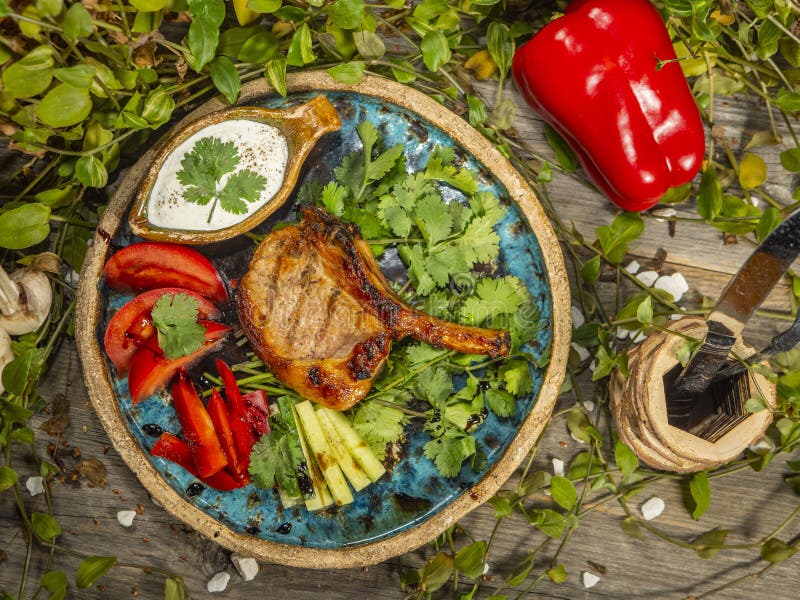 Meat on the Bone with Vegetables in a Craft Plate. White Sauce Stock ...