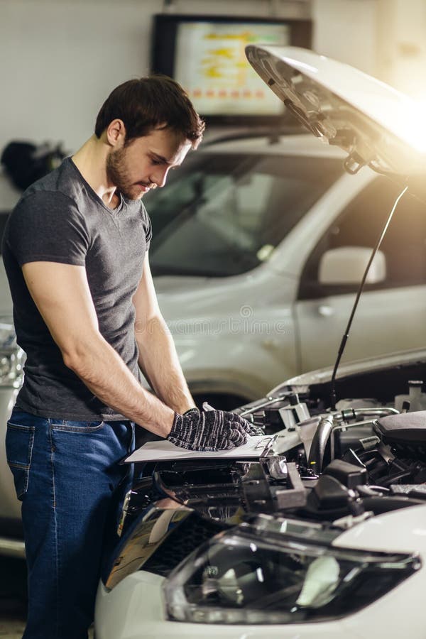 Mechachic Checking on Car Engine and Taking Notes in Clipboard Stock ...
