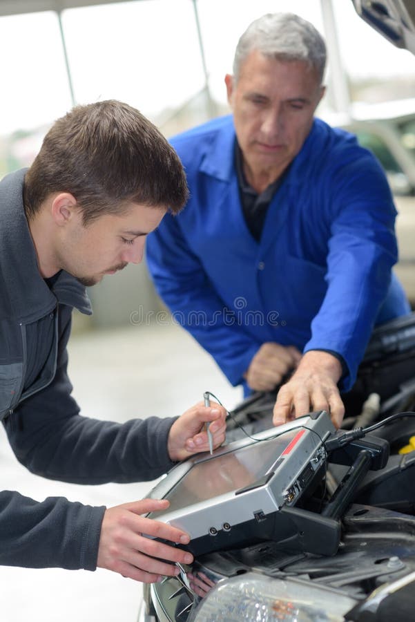 Mechanic and Apprentice Working on Car with Computer Stock Image ...