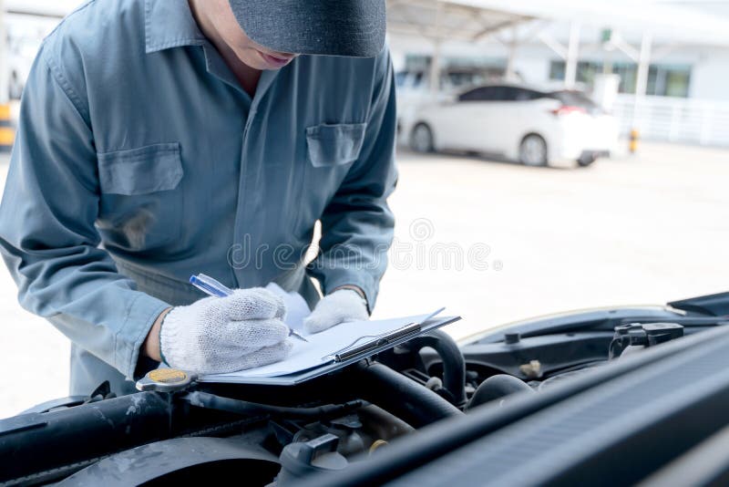 A Mechanic Checking on a Car Engine and Taking Notes Stock Image ...