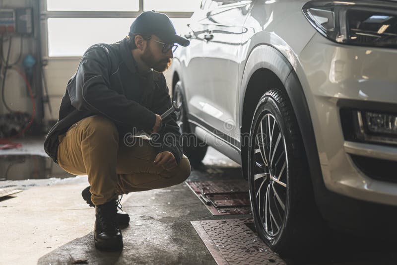 A Mechanic Checking Geometry and Suspension of a Car Wheel Using Tools ...