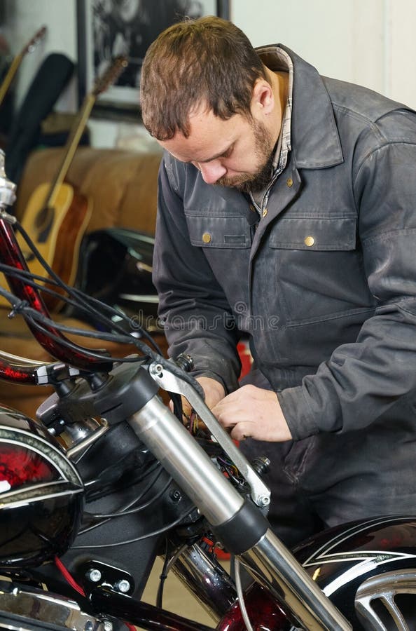 The Mechanic Connects the Electrical Cables of the Motorcycle. Vertical ...