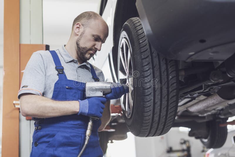 Mechanic Doing a Wheel Replacement Using a Pneumatic Wrench Stock Image ...