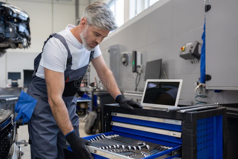 Mechanic in Garage Working on Car Maintenance Using Laptop for Engine ...