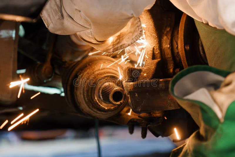 A Mechanic Grinding Metal Components Beneath a Vehicle in a Workshop ...