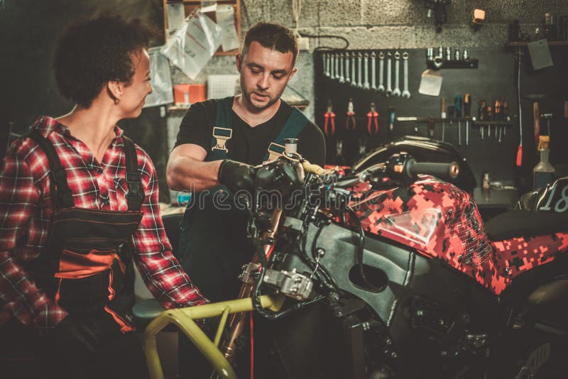 Mechanic and His Helper Repairing a Motorcycle in a Workshop Stock ...