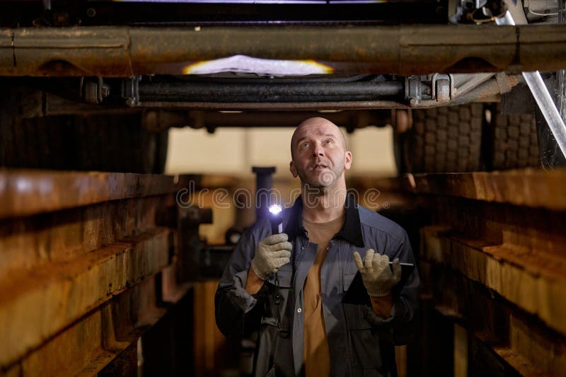 Mechanic Inspecting Car Underneath with Flashlight Stock Image - Image ...