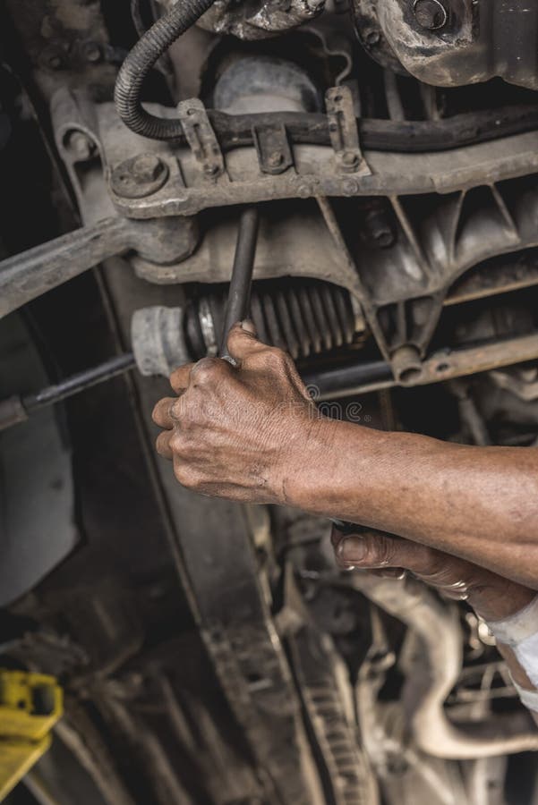 A Mechanic Inspects the Engine Support Underneath a Car, Tightening it ...