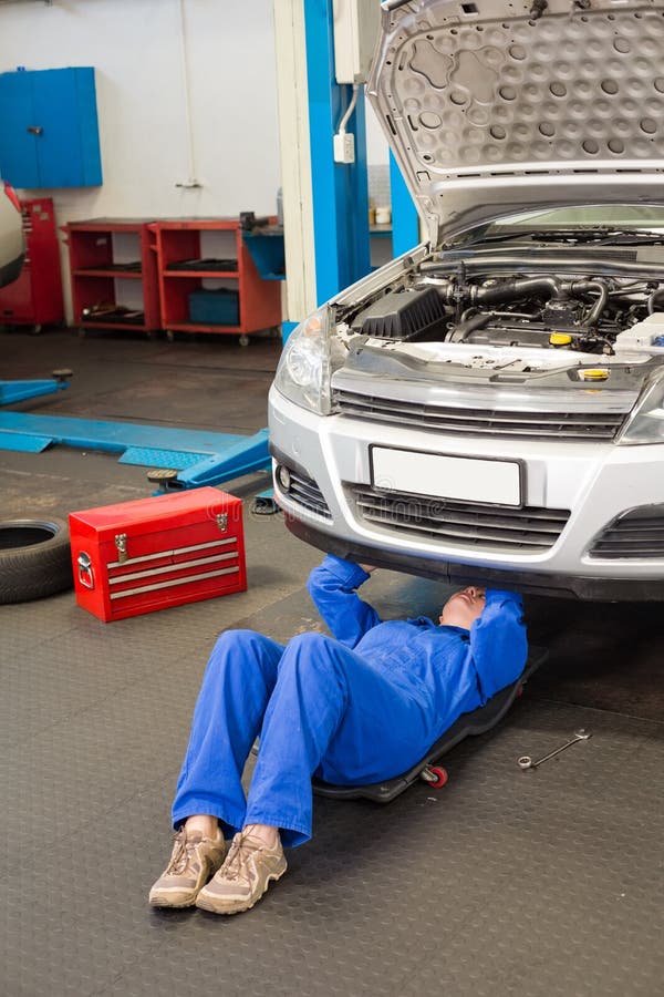 Mechanic Lying Down and Working Under Car at Auto Service Garage ...