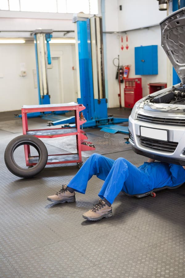 Car Mechanic Lying Down and Working Under Car in Auto Repair Service ...