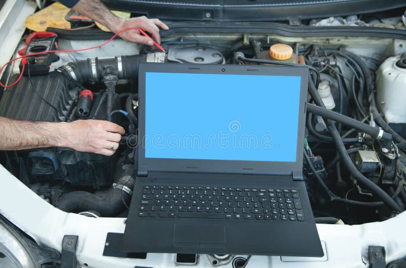 Mechanic with a Multimeter Testing Car Engine. Laptop on Car Engine ...