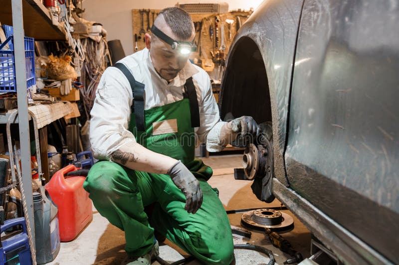 Mechanic Performing Brake Repair in a Dimly Lit Workshop Stock Photo ...