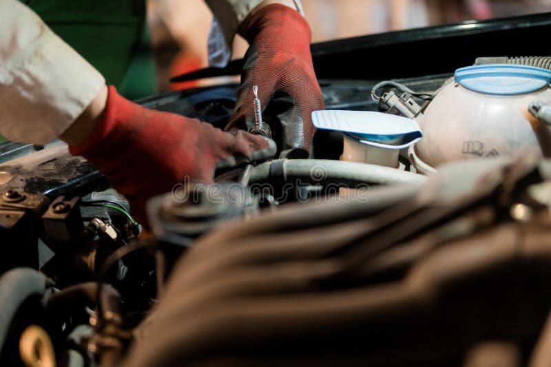Mechanic Performing Maintenance on a Car Engine Under Dim Lighting ...