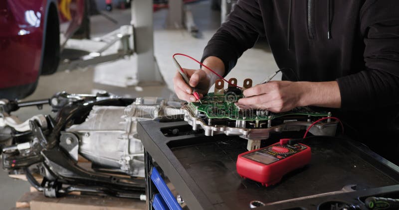 Mechanic Repairing Electric Car Engine with Voltmeter in Workshop Stock ...