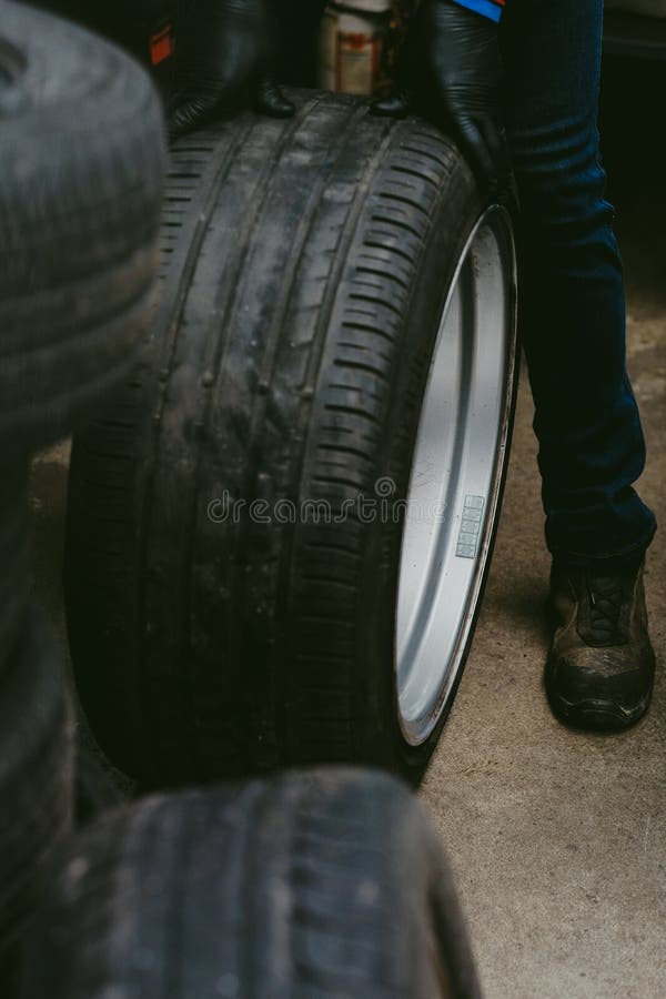 Mechanic Rolling a Car Wheel on the Ground in a Workshop Stock Photo ...