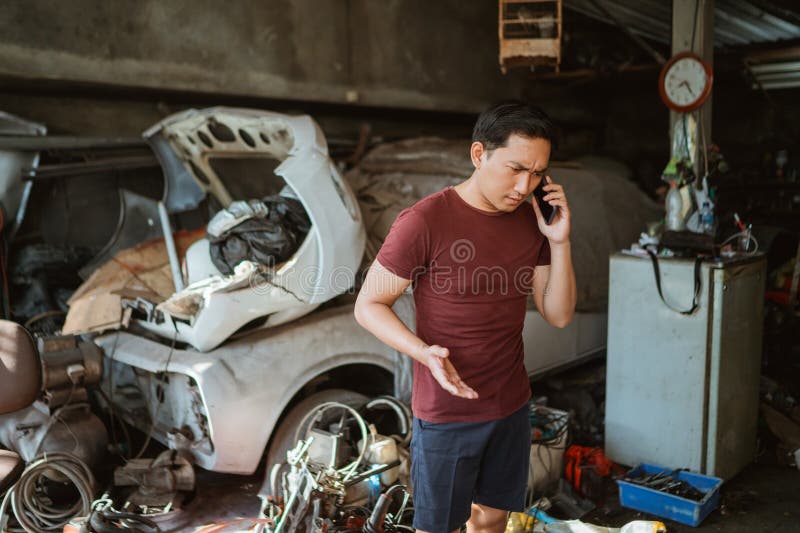 Mechanic Taking a Cell Phone Call Standing in an Old Garage Stock Image ...