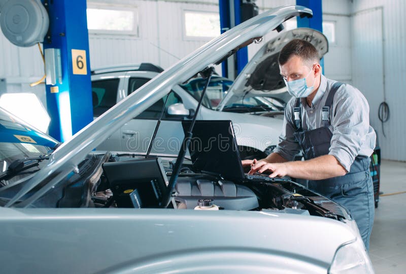 Mechanics in Uniform and Protective Masks Work in a Car Workshop. Stock ...