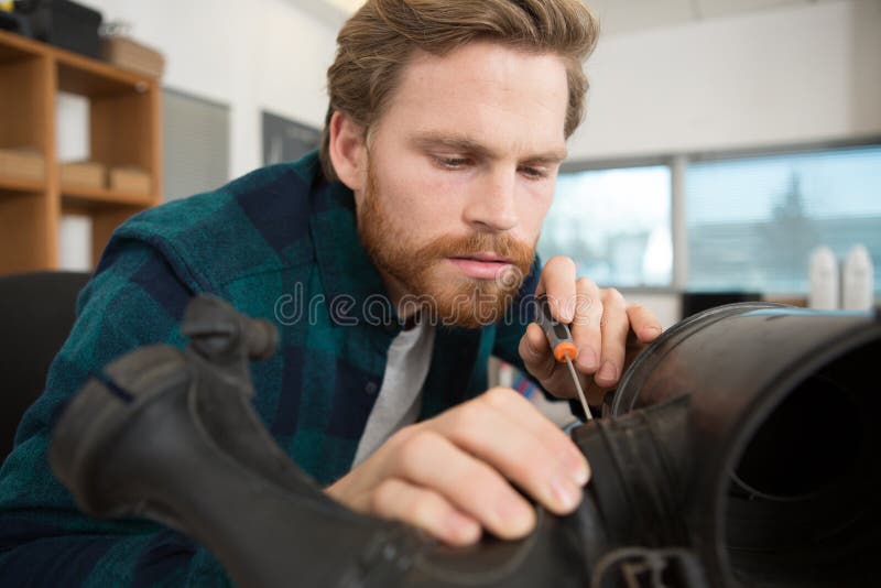 Mechanic Using Screwdriver To Assemble Parts in Workshop Stock Photo ...