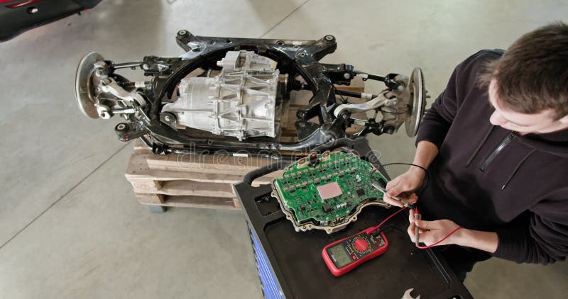 Mechanic Testing Electronic Unit of Disassembled Electric Car Engine ...