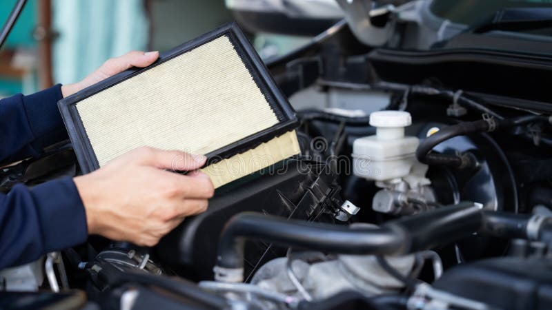 A Mechanic is Working on a Car Engine and Holding a Filter. the Concept ...