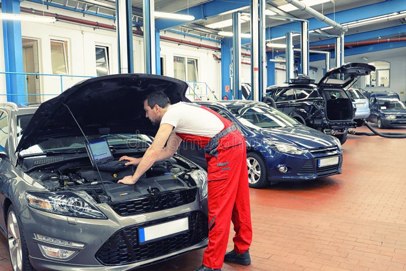 Mechanic in a Workshop Checks and Checks the Electronics of the Car ...