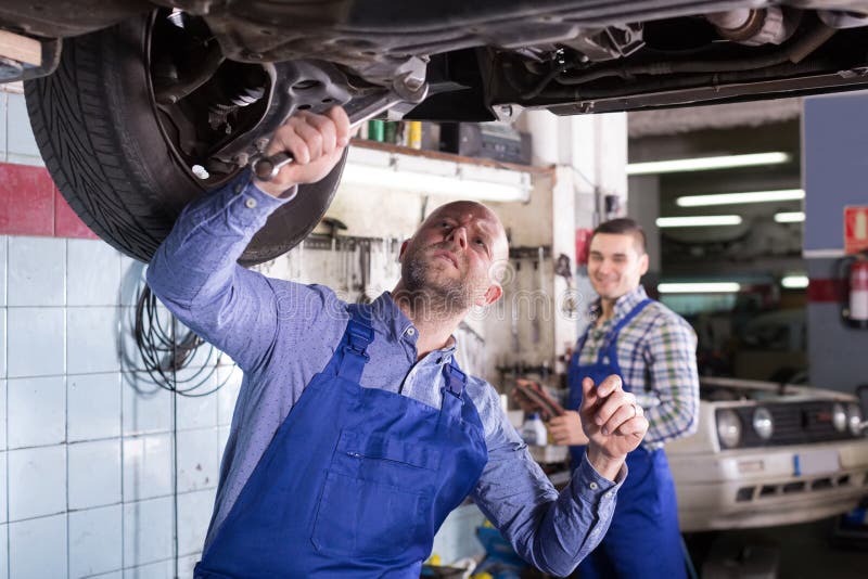 Two Mechanics in Car Fixing Workshop Stock Image - Image of smiling ...
