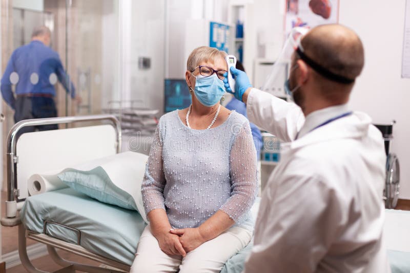 Medic Using Digital Thermometer To Check Temperature of Senior Patient ...
