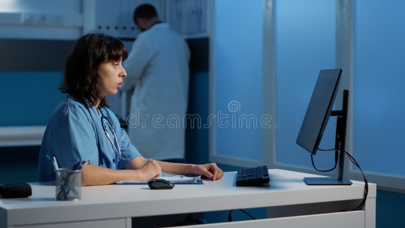 Medical Assistant Checking Disease Report on Computer while Working at ...