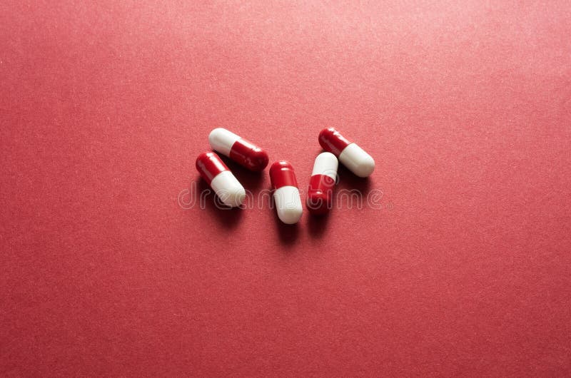 Medical Background, Red-white Capsules on a Red Background. Top View of ...