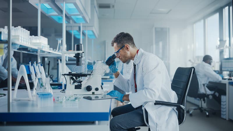 Medical Development Laboratory: Caucasian Male Scientist Looking Under ...
