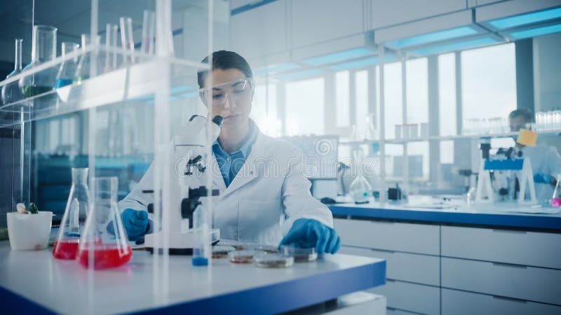 Medical Development Laboratory: Female Scientist Using Microscope and ...