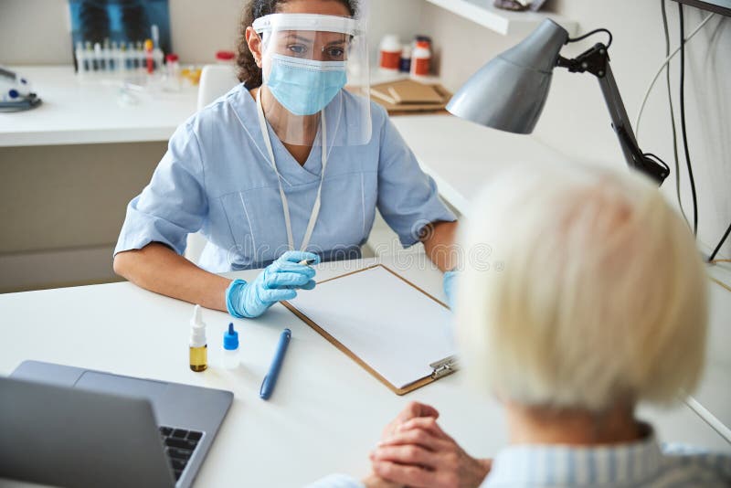 Medical Professional Looking with Interest at an Elderly Client Stock ...