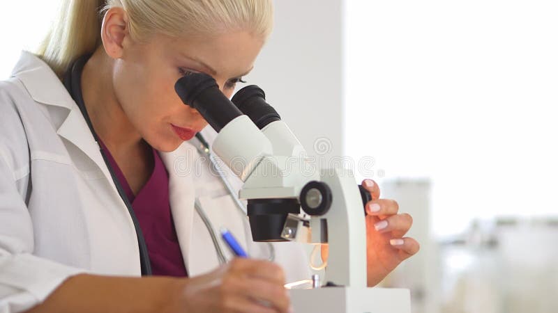 Medical Researcher Using Microscope and Writing Notes Stock Video ...