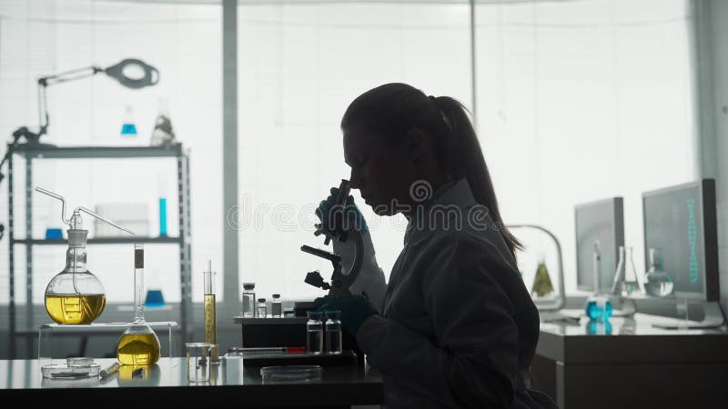 Side View of a Dark Silhouette of a Female Scientist Looking Under a ...