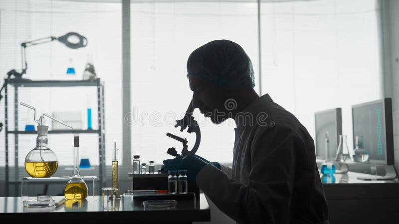 A Young Scientist in a Research Laboratory Examines a Sample on a ...