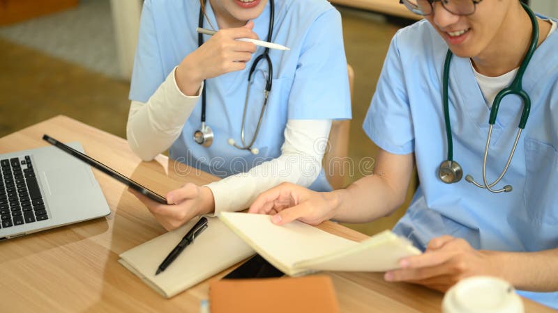 Medical Students in Blue Scrubs Reviewing a Notes and Using Digital ...