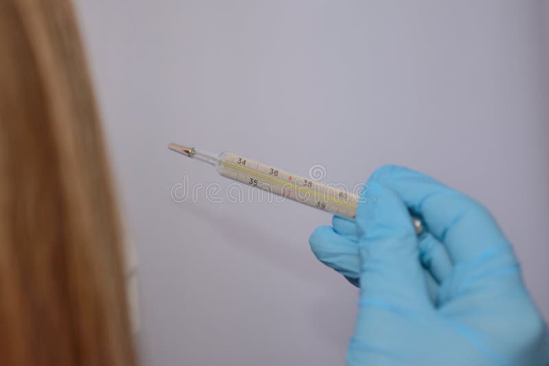 A Medical Thermometer in a Gloved Hand for Measuring Body Temperature ...