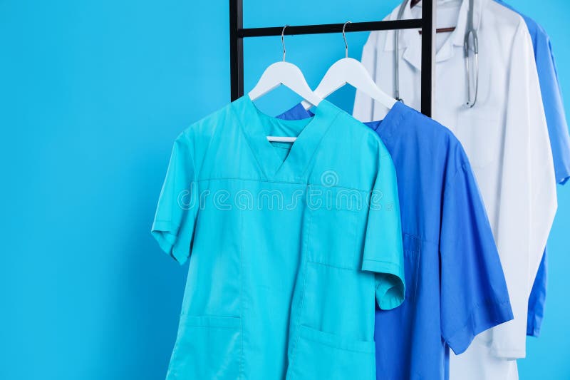 Medical Uniforms on Metal Rack Against Light Blue Background Stock ...