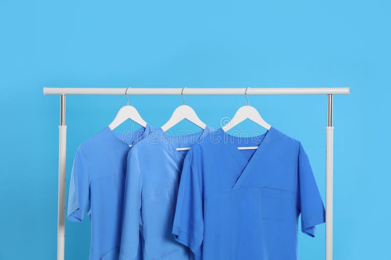 Medical Uniforms on Rack Against Light Blue Background Stock Image ...
