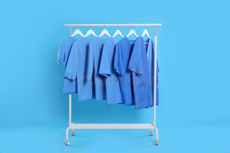 Medical Uniforms on Rack Against Light Blue Background Stock Photo ...