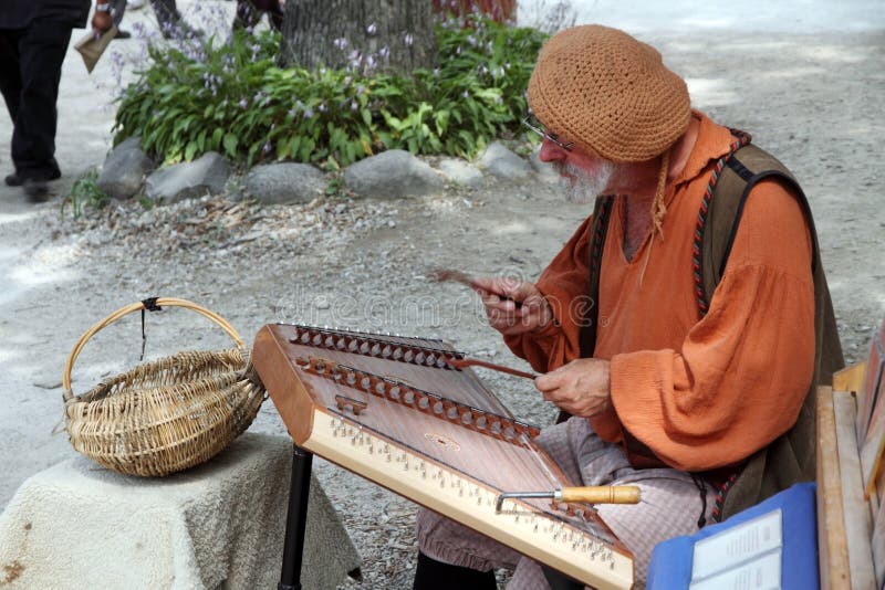 Medieval Dressed Musician Performs on a String Percussion Instrument ...