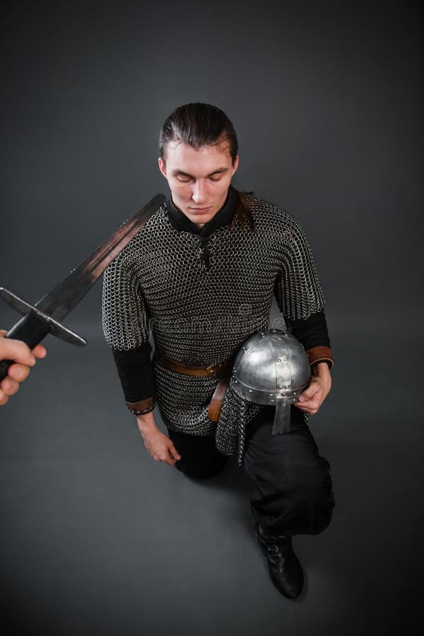 A Medieval Warrior in Chain Mail Sits on His Knee with a Helmet in His ...