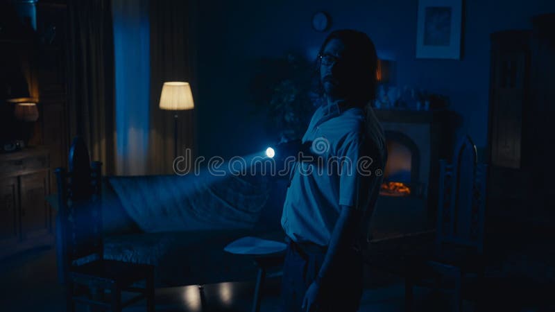 Medium-full Photo Capturing a Man Walking Around a Dark Room in Search ...