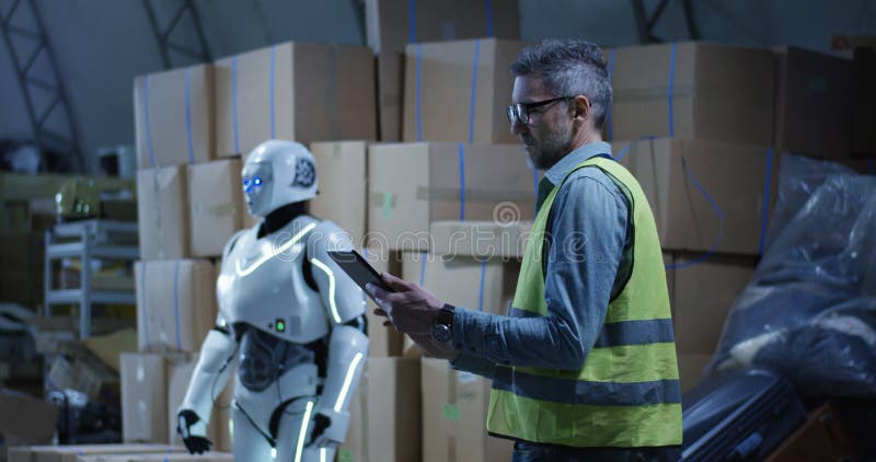 Man Watching Robot Working in a Warehouse Stock Photo - Image of ...