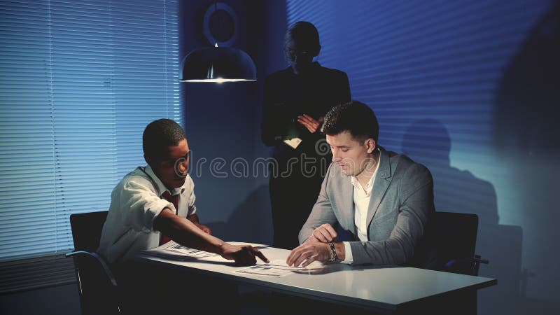 Medium Shot Of African Detective Questioning Suspect Caucasian Man In