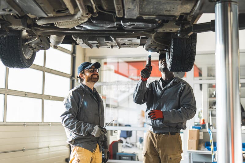 Medium Shot of Multi-ethnic Mechanics Working Underneath the Car in the ...