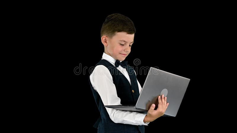 Smiling Boy in a Bow Tie and Waistcoat Using Laptop Computer while ...