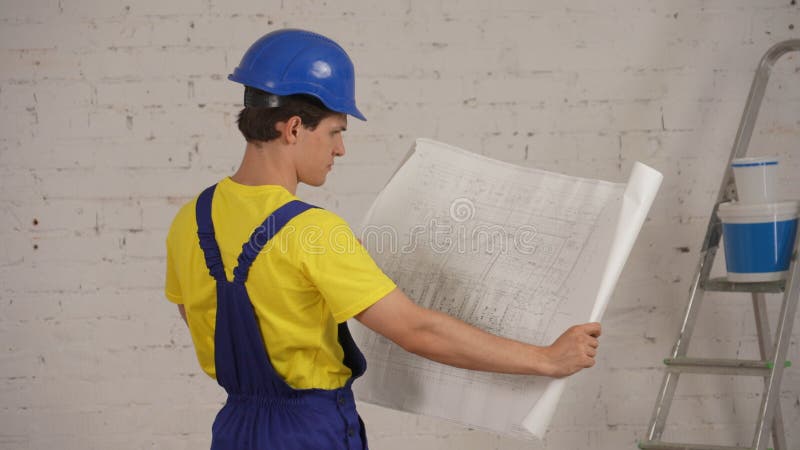 Medium Shot of a Smiling Young Construction Worker Looking at the Plan ...