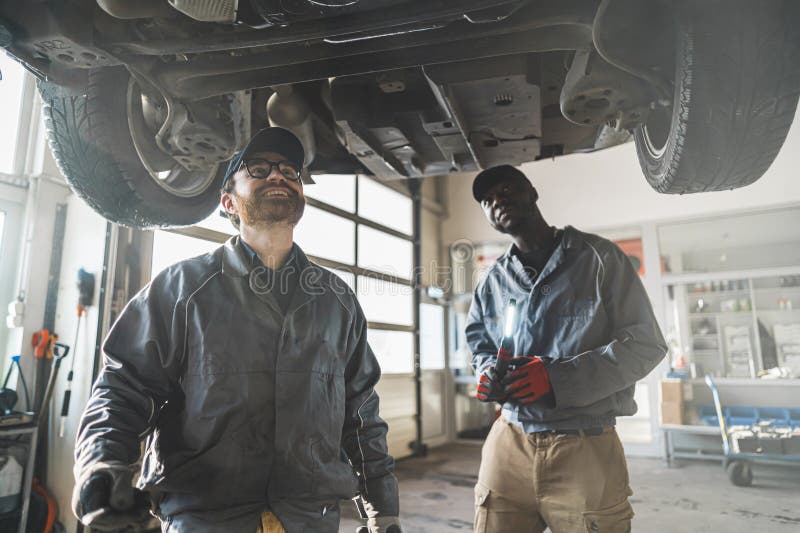 Medium Shot of Two Mechanics Inspecting Car S Underside Stock Photo ...